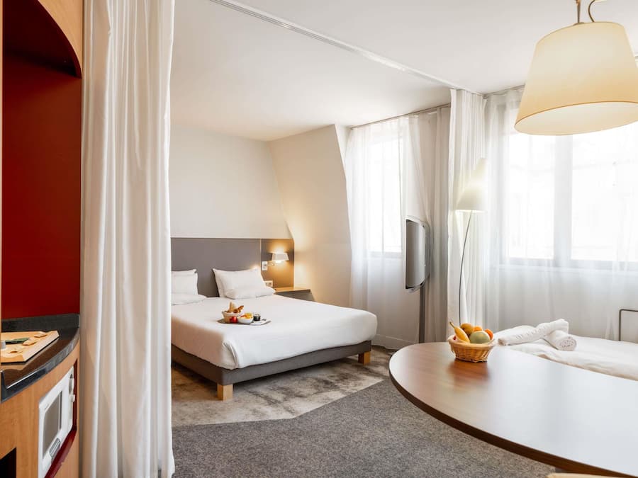 Quarto de hotel com uma cama, mesa de cabeceira e uma pequena mesa de jantar.