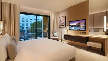 Quarto de hotel moderno com uma cama grande, uma escrivaninha, uma cadeira, uma televisão e uma varanda com vista para a cidade.