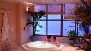 Um quarto de spa com uma banheira grande, um banco e plantas em vasos.
