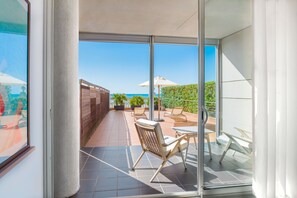 Varanda com vista para o mar, móveis de exterior e plantas em vasos.