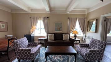 Uma sala de estar com sofá, duas poltronas, uma mesa de centro e um tapete estampado.