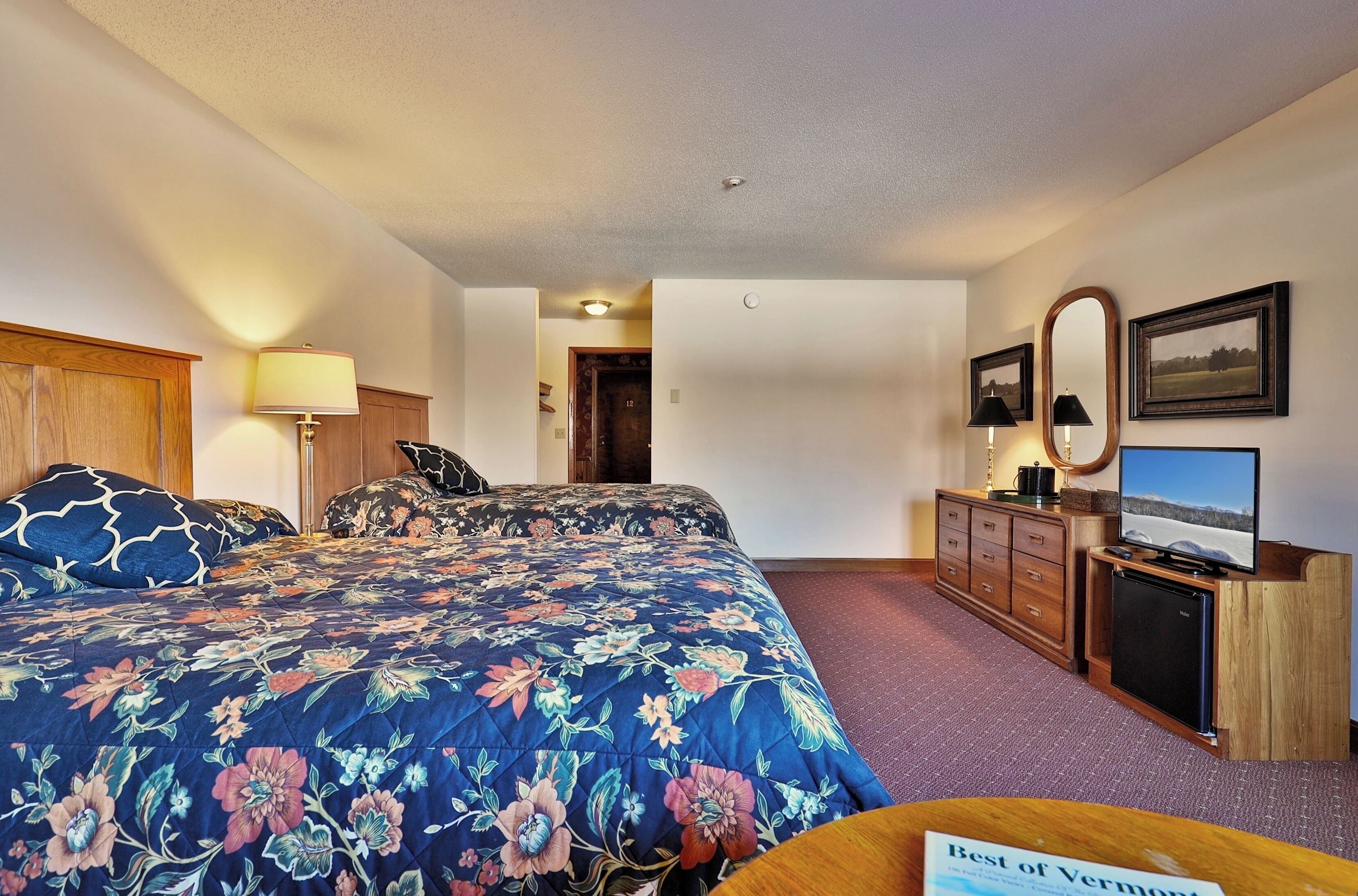 Quarto de hotel com uma cama grande, penteadeira, televisão e um aviso que indica ser o melhor quarto de Vermont.