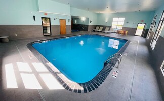 Piscina interna com água cristalina, pistas demarcadas e chão revestido de azulejos.