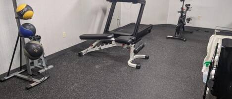 Uma academia com esteira, bicicleta ergométrica e diversos bolas de exercício.