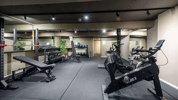 Uma academia com equipamentos de ginástica, espelhos e um painel espelhado.