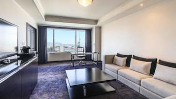 Quarto de hotel moderno com uma grande janela, um sofá, uma mesa de centro e uma escrivaninha.