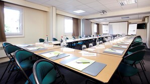 Uma sala de conferência com uma mesa comprida, placas de identificação, cadeiras e telas de apresentação.