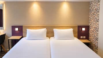 Cama de casal com lençóis brancos, cabeceira de madeira e duas luminárias de cabeceira.