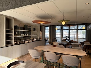 Um interior moderno com área de bar, assentos e amplas janelas.
