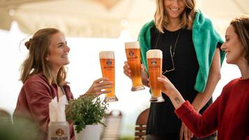 Três pessoas brindando com copos de cerveja.