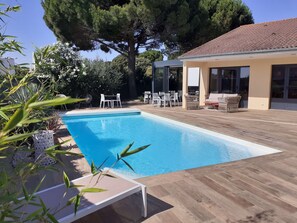 Piscina com espreguiçadeiras e área de pátio.