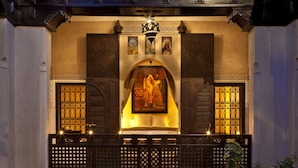 Um edifício tradicional com varanda, uma estátua e uma cama visível no interior.