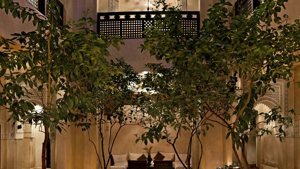 Pátio interno com fonte, área de estar e iluminação decorativa.