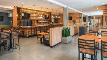 Um espaço de bar moderno com mobiliário de madeira, uma televisão e diversas garrafas.