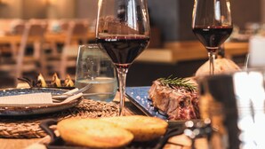 Uma mesa de jantar com duas taças de vinho, um prato com comida e uma garrafa de vinho.