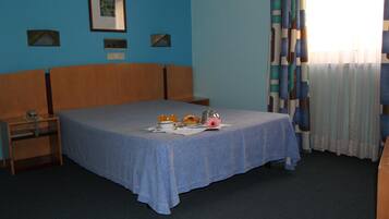 Quarto de hotel com cama, mesa de cabeceira e janela com cortinas.