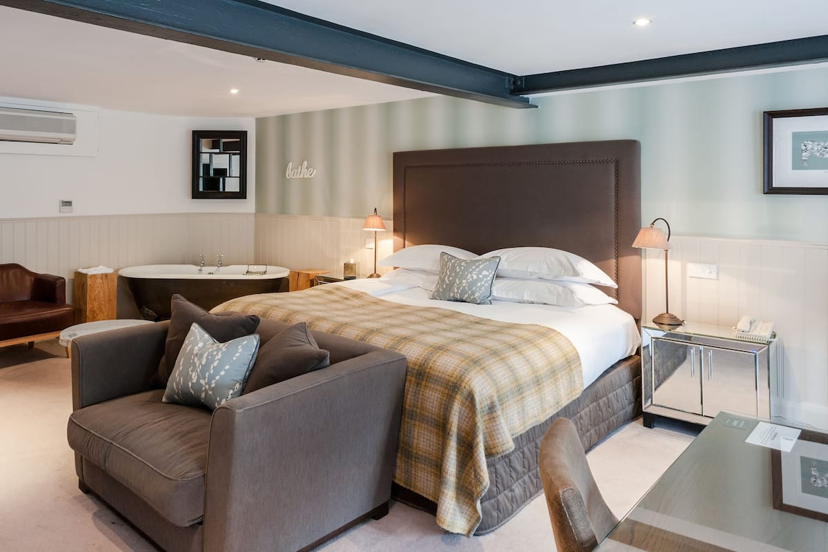 Quarto moderno com uma cama grande, um sofá, uma mesinha e uma cadeira.