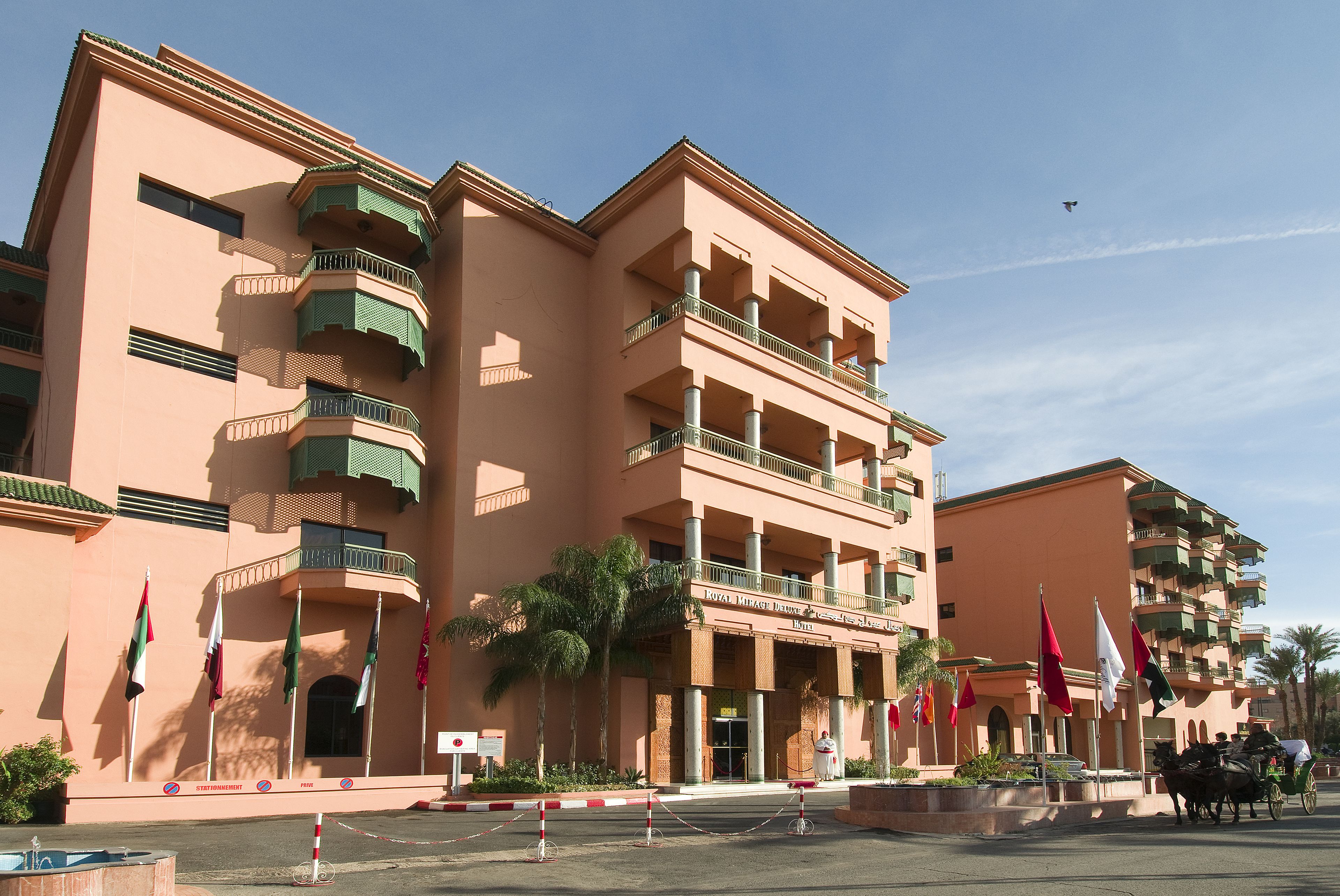 Hotel de vários andares com varandas, bandeiras e um céu claro.