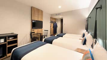 Quarto de hotel com duas camas, uma televisão, uma escrivaninha e uma cadeira.