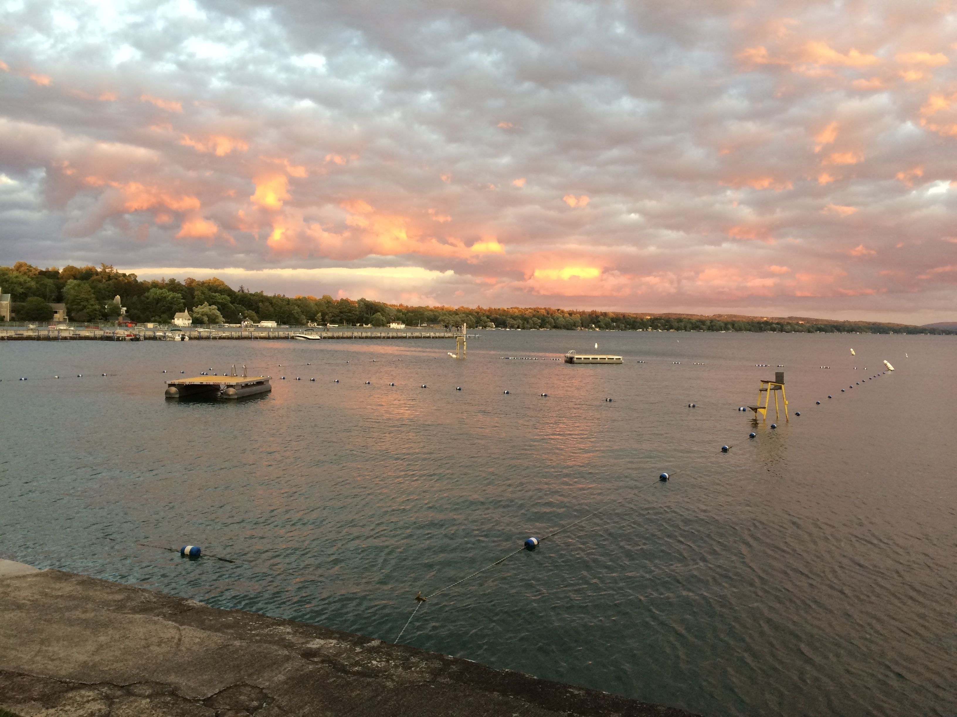 Um cenário calmo à beira-mar, com um cais, barcos e bóias.