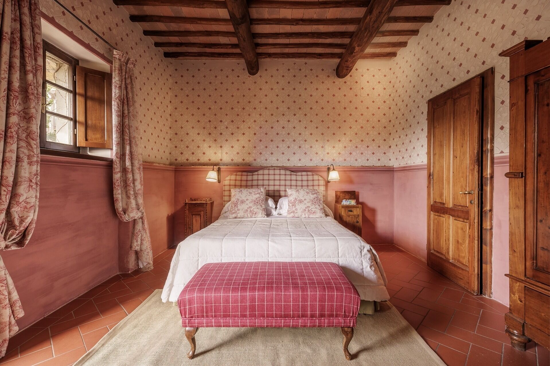 Quarto com cama, um banquinho, mesa de cabeceira e guarda-roupa.