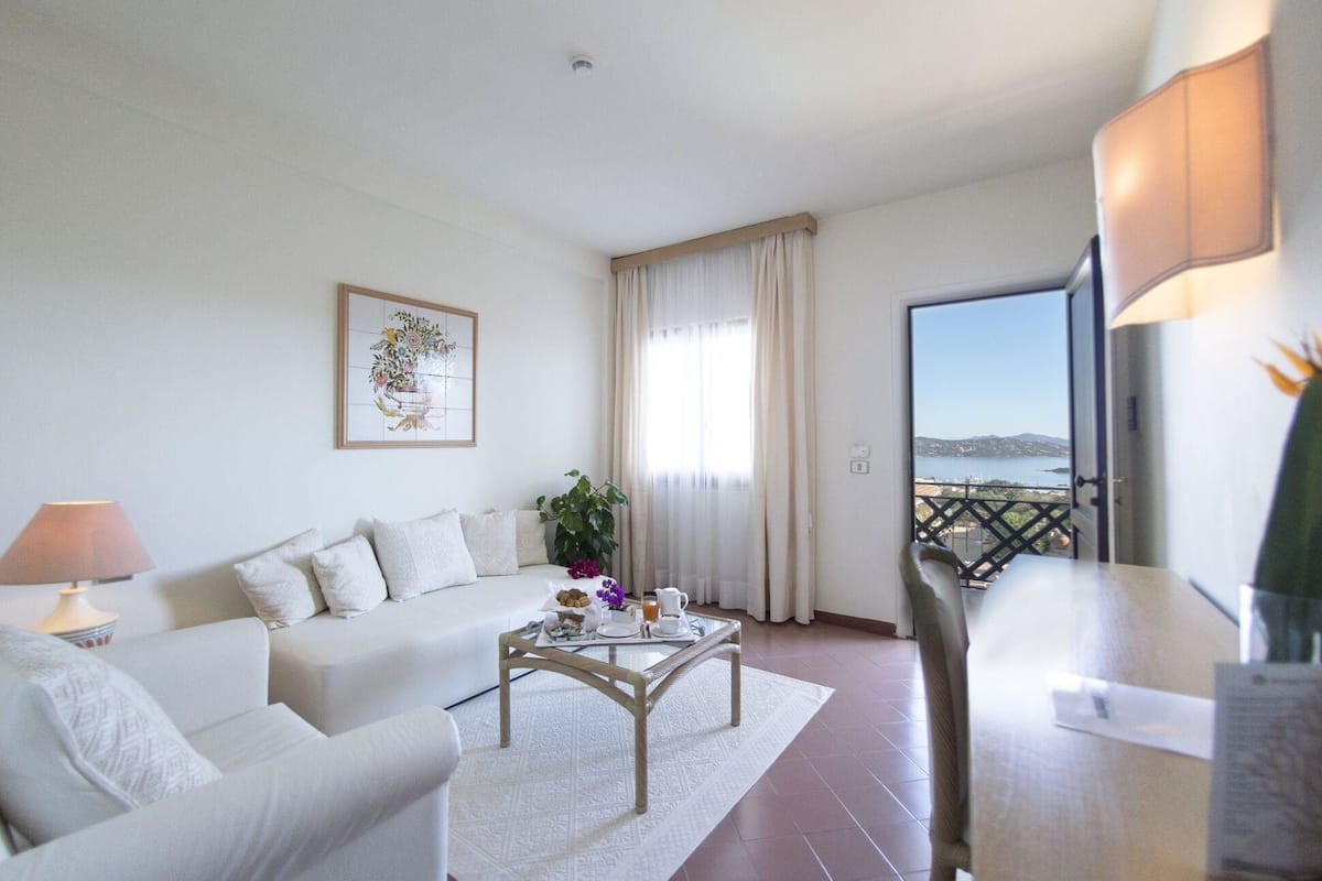 Uma sala de estar moderna com sofá, mesa de centro e vista para o mar.