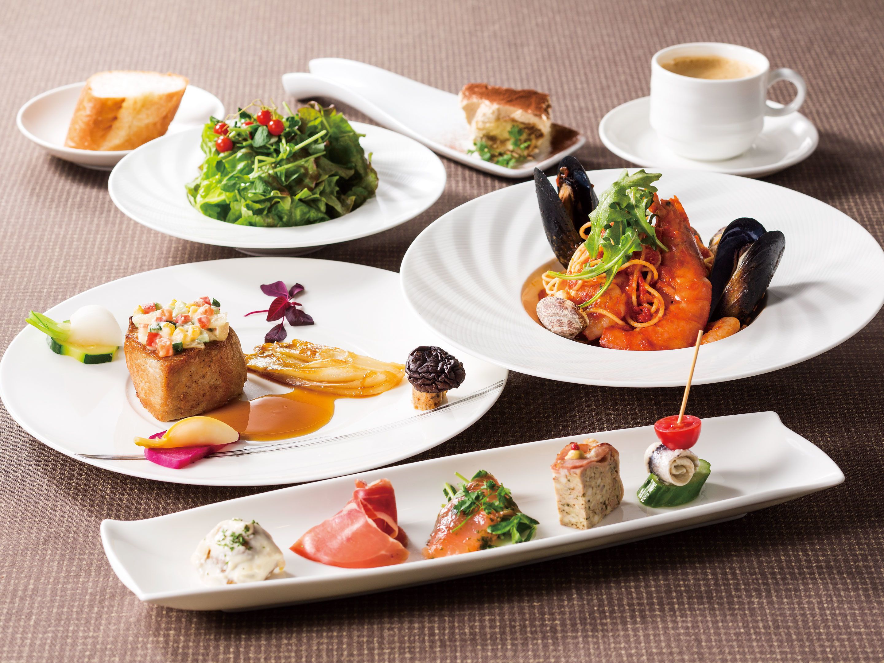 Diversos pratos servidos em travessas sobre uma mesa, incluindo frutos do mar, saladas e sobremesas.