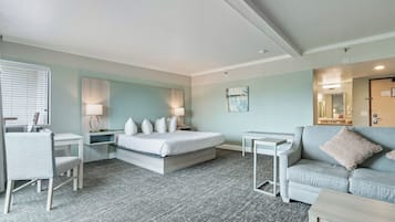 Quarto de hotel com cama, escrivaninha, cadeira, sofá e pequena mesa.