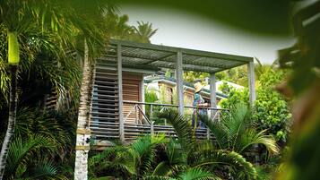 Uma casa moderna com varanda coberta, rodeada por vegetação tropical exuberante.