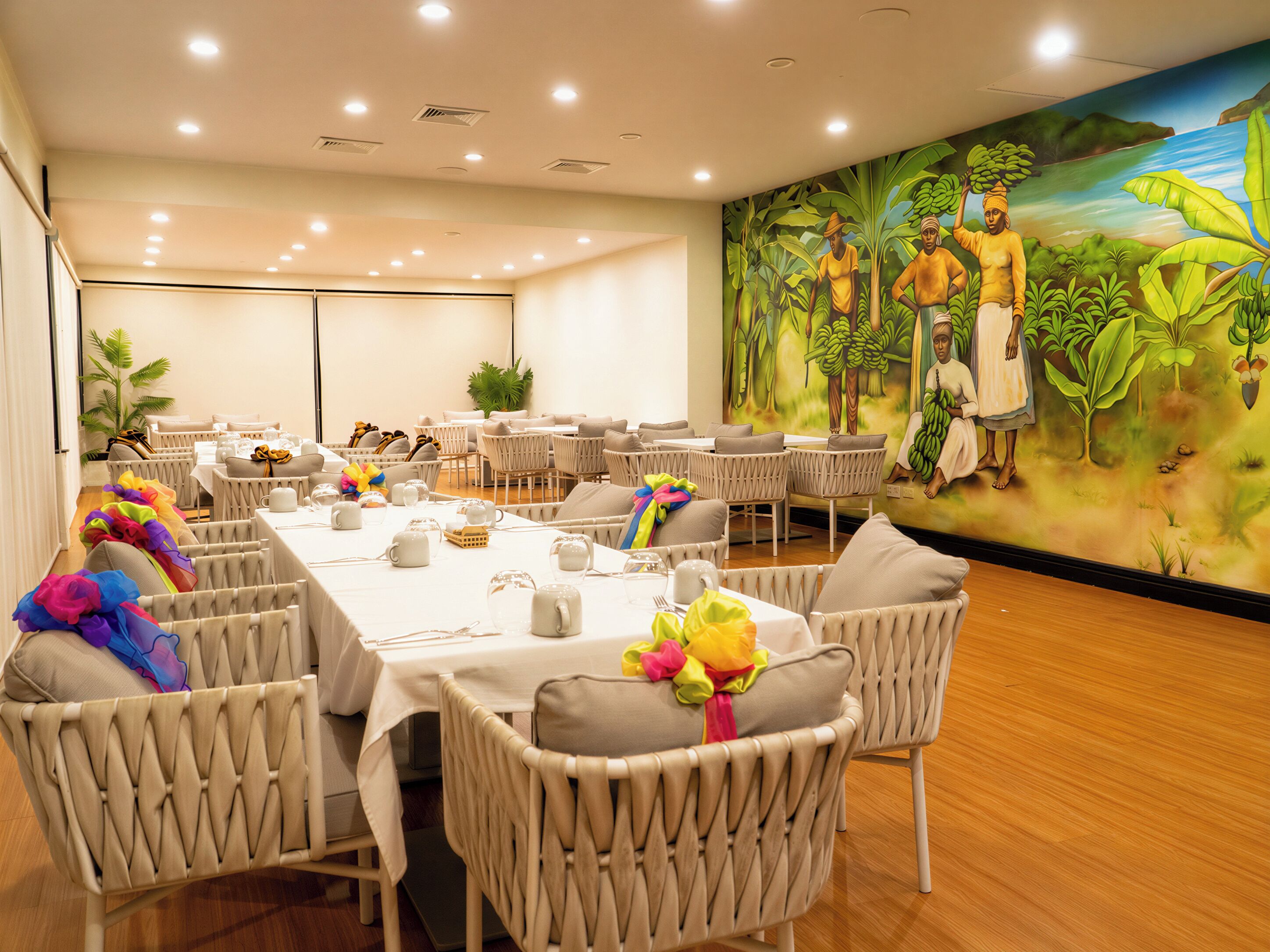 Uma sala de conferências com uma mesa comprida, cadeiras e um mural retratando figuras tropicais.