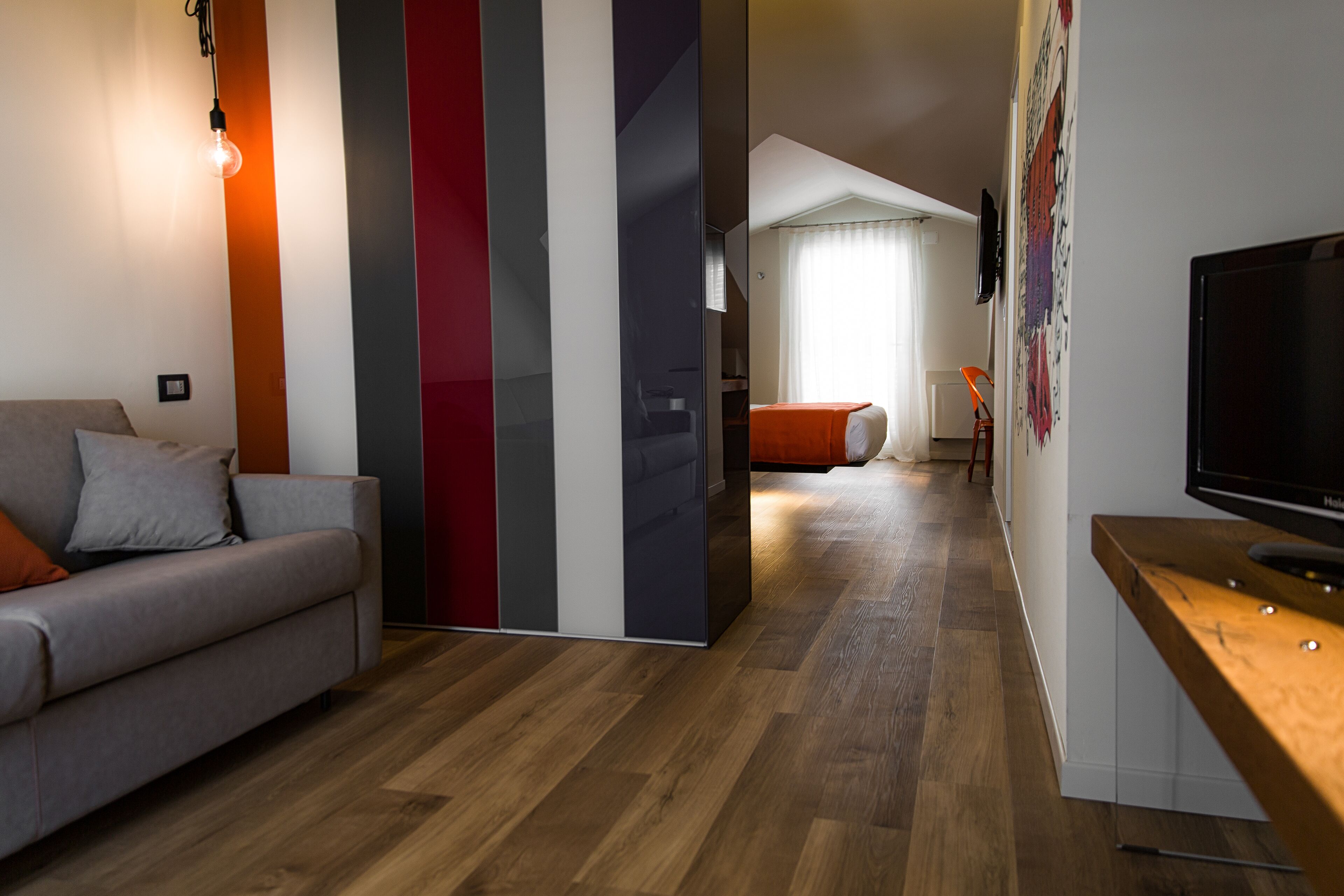 Uma sala de estar moderna com um sofá, uma televisão e piso de madeira.