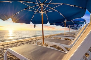 Na praia, praia de areia branca, espreguiçadeiras, guarda-sóis de praia 