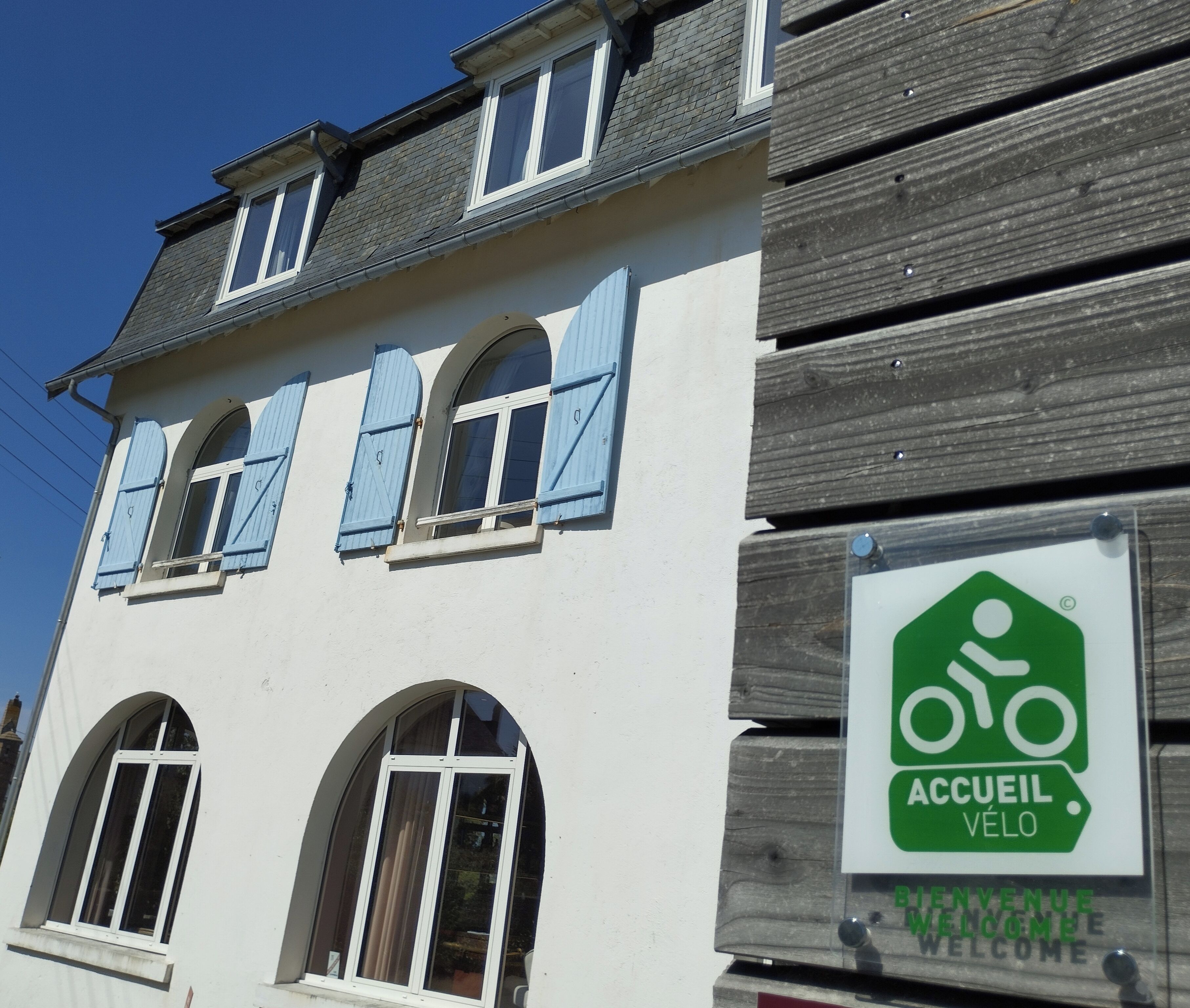 Um edifício com janelas em arco e um aviso indicando acomodação para ciclistas.