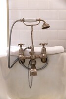 Um banheiro em estilo vintage com uma banheira de patinhas, chuveiro e porta-toalhas.