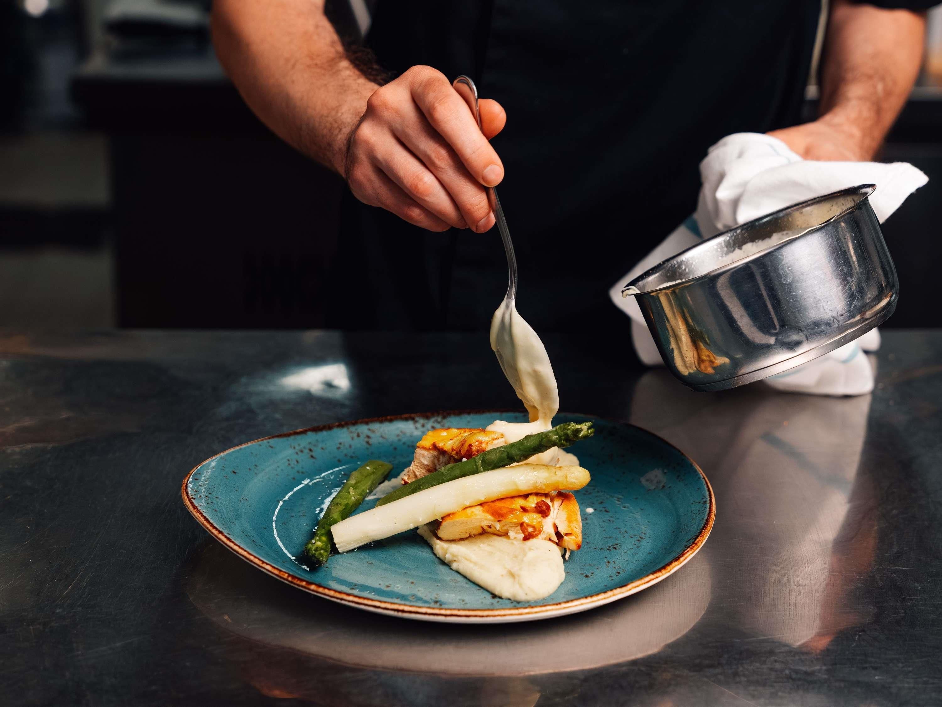 Um chef regando um prato com comida.