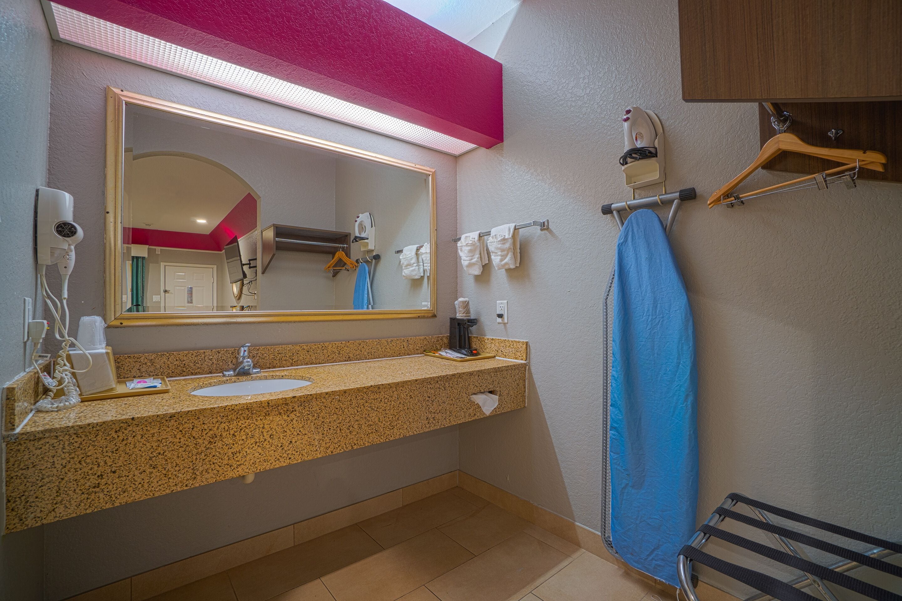 Casa de banho com bancada de granito, pia, espelho, porta-toalhas e secador de cabelo.