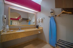 Casa de banho com bancada de granito, pia, espelho, porta-toalhas e secador de cabelo.