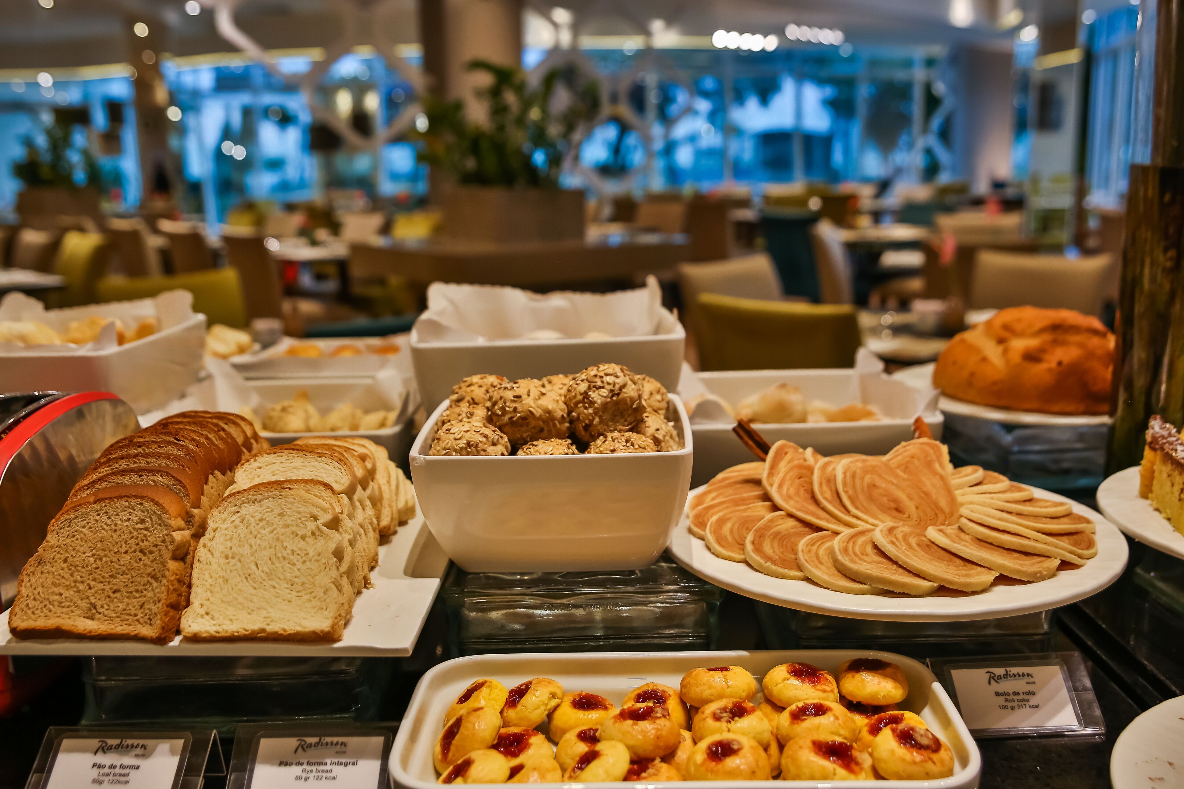 Um buffet com diversos pães e doces.