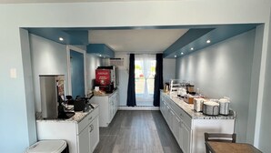 Cozinha pequena com geladeira, micro-ondas e máquina de café.