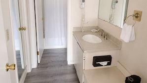 Casa de banho com lavatório, espelho, porta-toalhas e secador de cabelo.