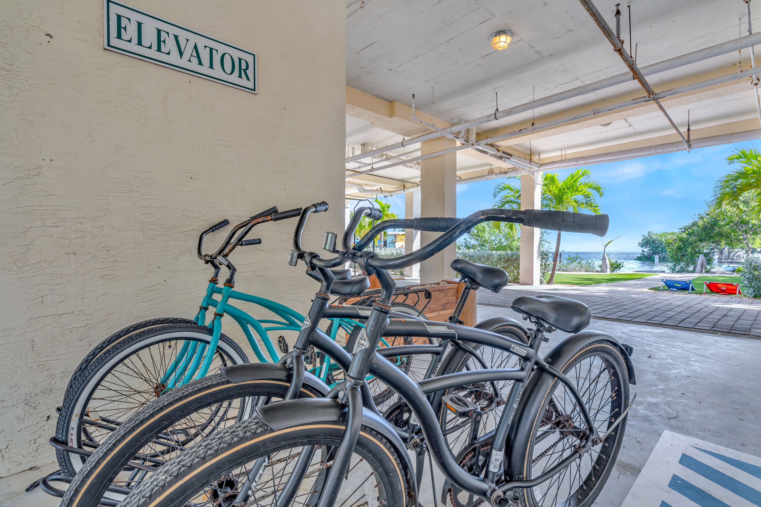 Bicicletas estacionadas perto de um elevador numa área externa coberta com vista para o oceano.