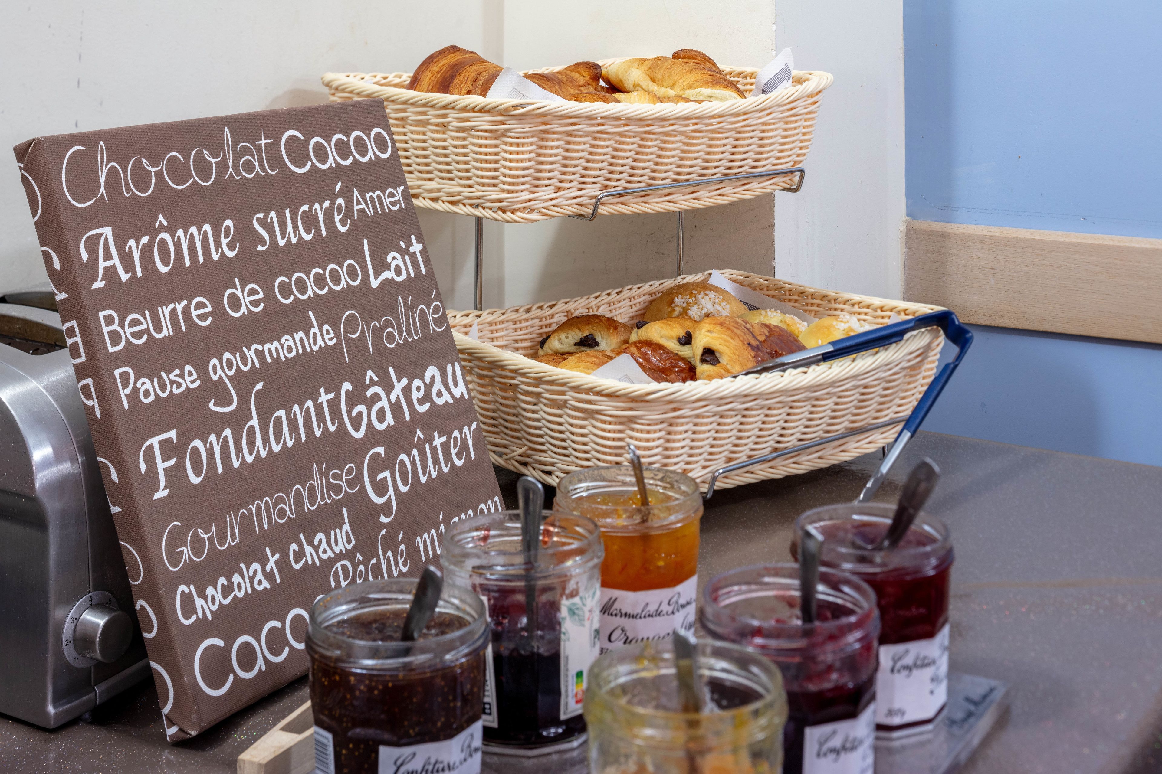 Exposição de produtos de chocolate e doces, incluindo uma placa com texto e cestas de produtos de panificação.