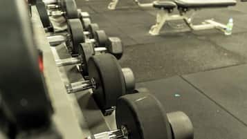 Vários halteres pretos dispostos em um suporte em uma academia.