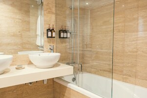 Uma casa de banho moderna com duas pias grandes brancas, um chuveiro com parede de vidro e um revestimento de mármore.