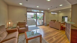 Uma sala de estar espaçosa com uma grande porta de vidro deslizante que dá para uma varanda externa, um sofá, uma mesa de centro e um painel de vidro.
