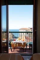 Varanda com mesa e cadeiras, vista para a cidade e para o mar.