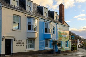 Um edifício com uma placa que diz "EATING SLEEPING DRINKING" e um mural lateral.