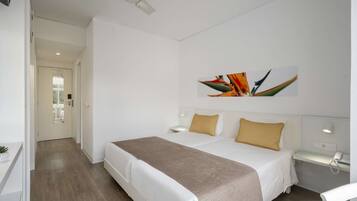Quarto de hotel com uma cama grande, mesa de cabeceira, escrivaninha e ventilador de teto.