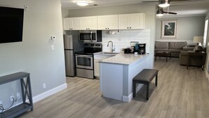 Uma cozinha moderna com eletrodomésticos de aço inoxidável, uma ilha central e um espaço de refeições com sofá e mesa de centro.