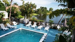 Área de piscina com espreguiçadeiras e vista para um lago.